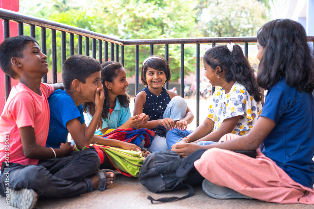 group of teenger children talking with friends while sitting at school ...