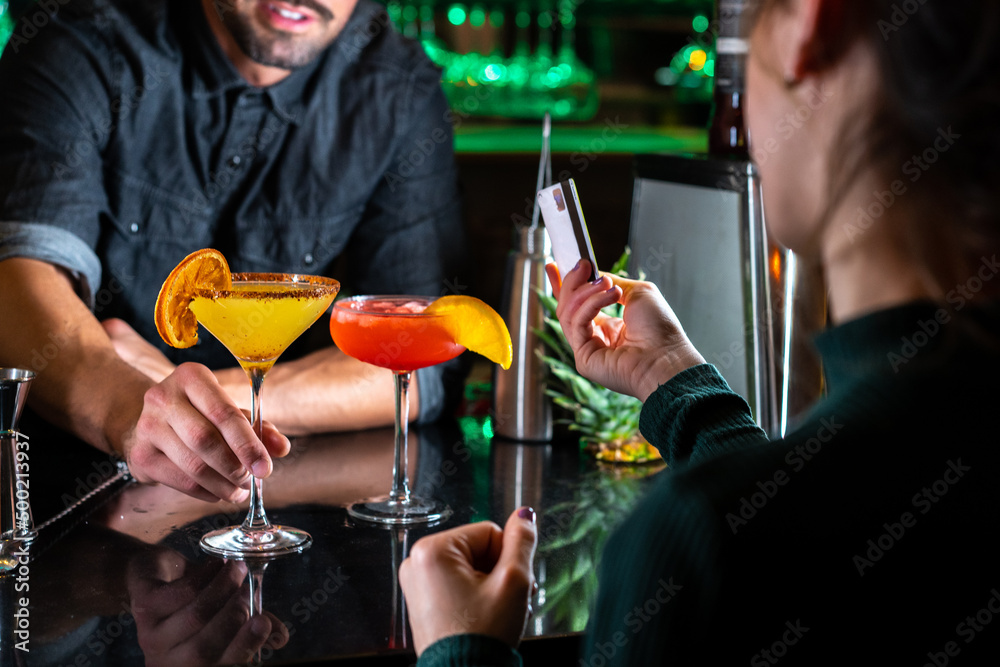 Waiter giving a cocktail while client shows her credit card in a night ...