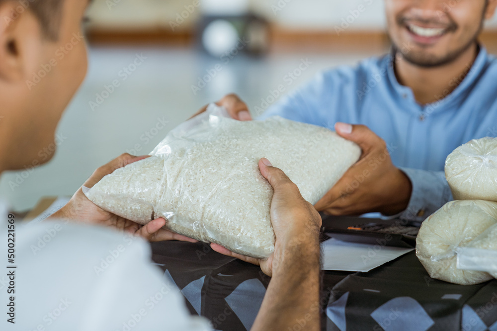 portrait of happy muslim man giving a rice as a food donation for zakat ...