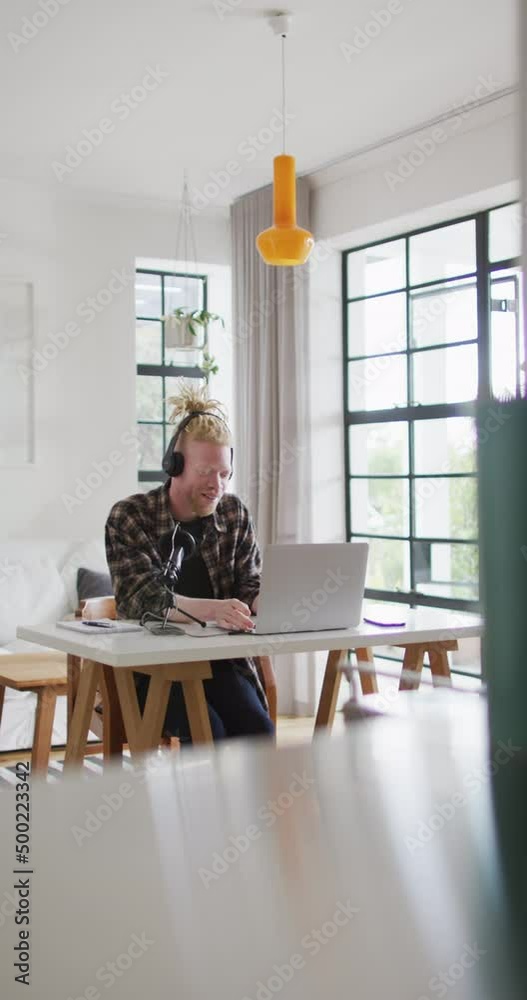 Vertical shot of an Albino man recording a podcast at home, talking to ...