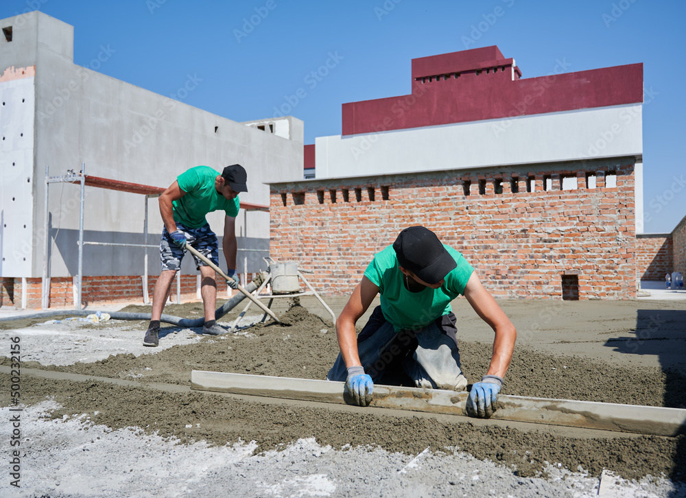 Contractors placing screed rail on the floor covered with sand-cement ...