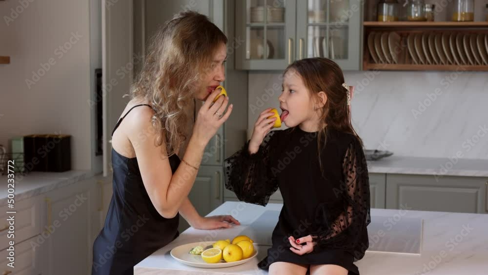 Funny family of mother and daughter trying lemons. Happy woman with her ...