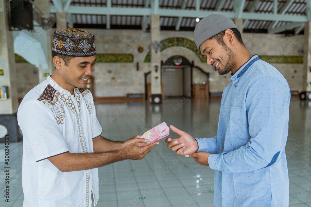 portrait of male muslim paying some zakat charity using cash at the ...