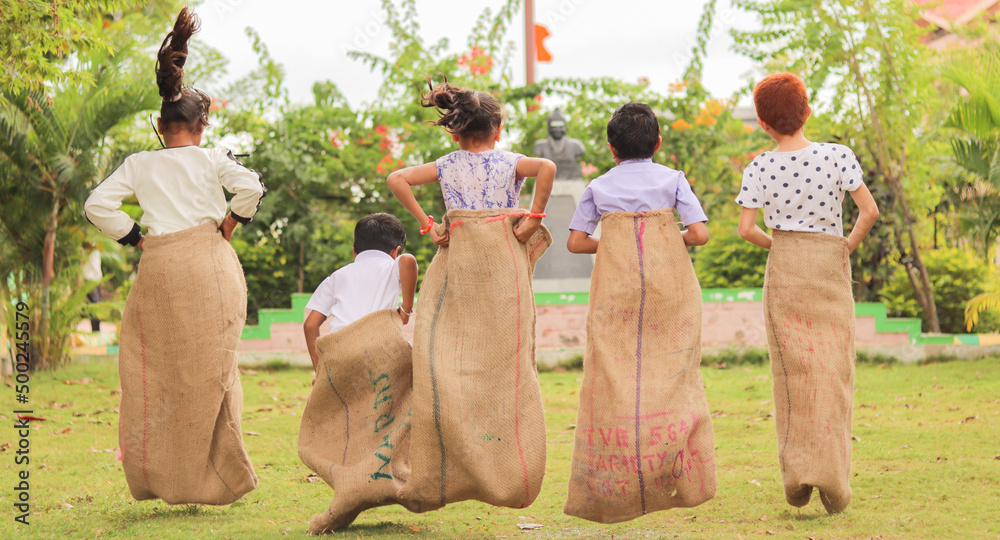 back view shot of Group of Childrens playing potato sack jumping race ...