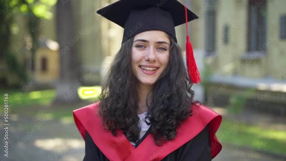Charming slim Caucasian young woman in mortarboard cap adjusting ...