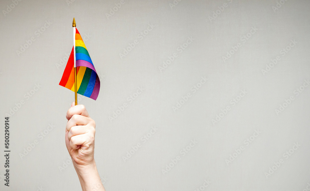 Person holding rainbow flag as symbol of tolerance in front of beige ...