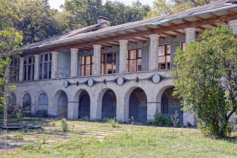 a long old building with windows and concrete columns and gray arches ...
