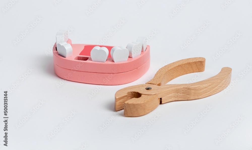 Forceps and wooden human jaw model. Teeth extraction, pulling procedure ...