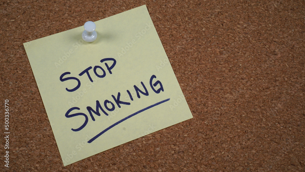 Note posted on a cork board with a reminder to stop smoking. Stock ...