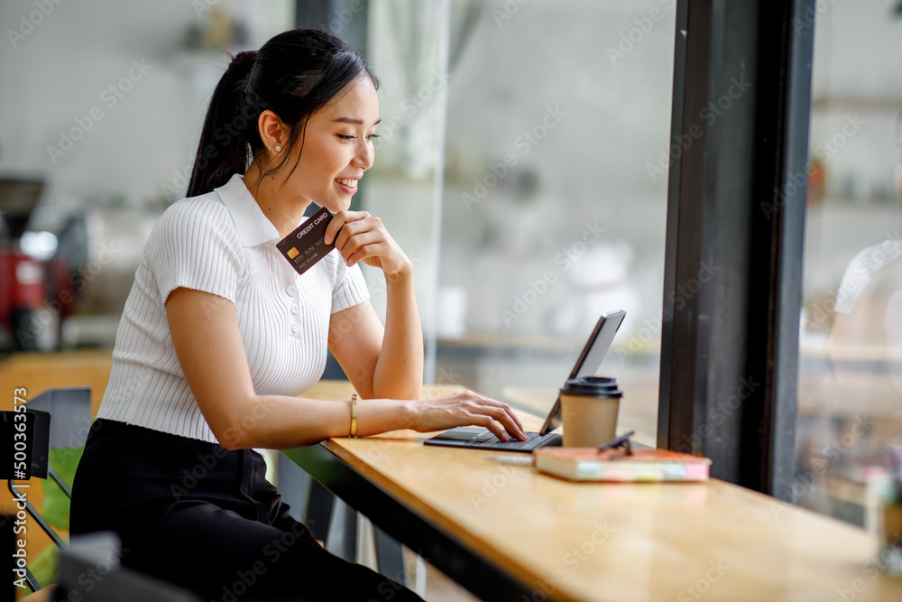 Women holding credit card and using tablet laptop computer at coffee ...