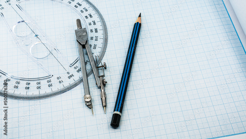 On blue graph paper are compasses, protractor, ruler, and a pencil ...