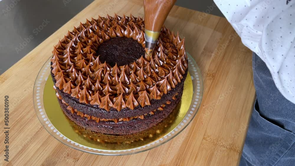 Pastry chef decorating a chocolate birthday cake with chocolate and a ...