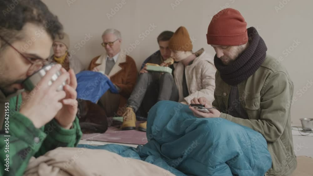 Slowmo portrait of bearded Caucasian refugee man using mobile phone to ...