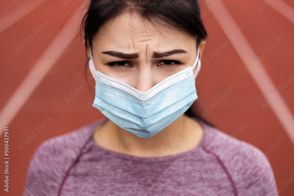 Woman dressed sports suit wear face blue disposable mask crying upset ...