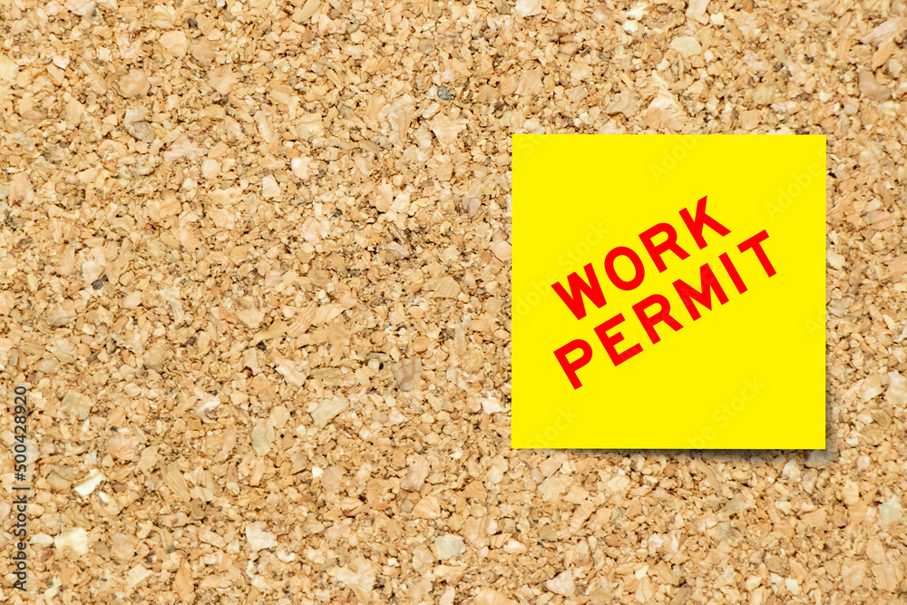 Yellow note paper with word work permit on cork board background with ...