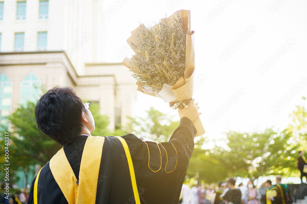 Happy Asian graduate student holding a beautiful bouquet of flowers in ...
