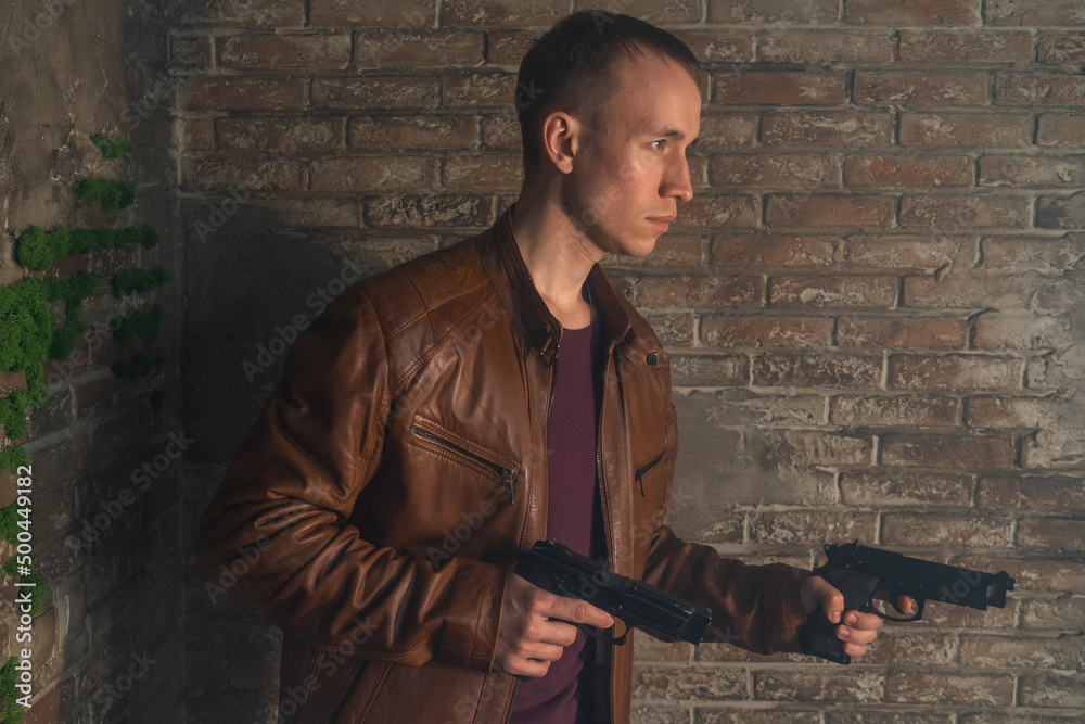 young guy with gun in leather jacket in profile Stock Photo | Adobe Stock