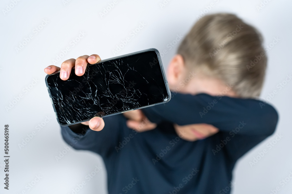 Scared teen boy with emotional expression showing broken smartphone ...