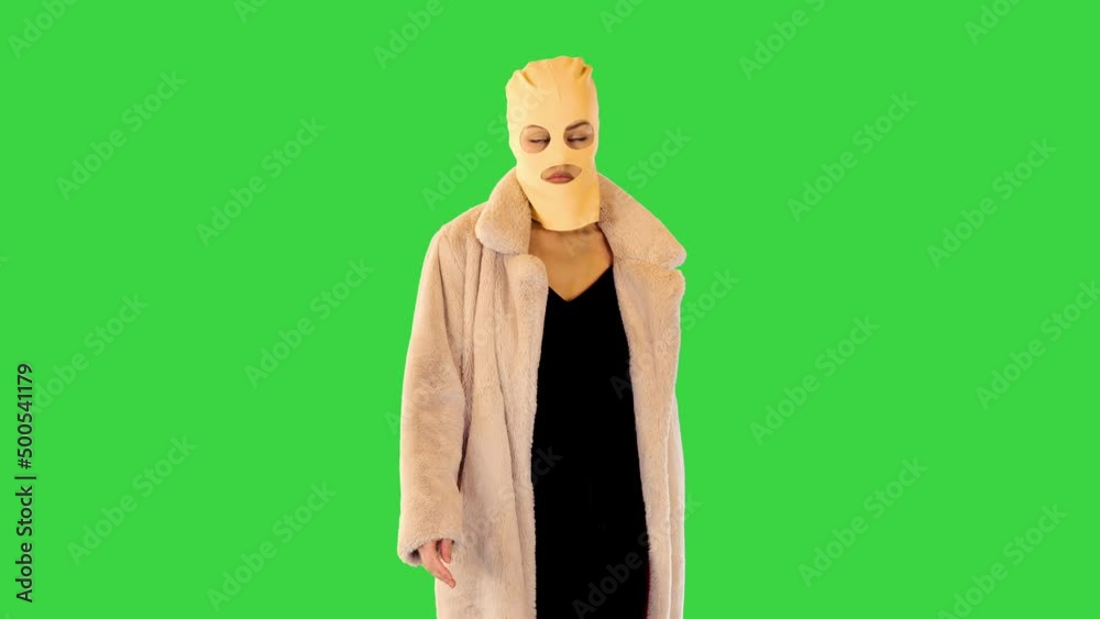 Girl in fur coat dancing slightly, adjusting her balaclava on a Green ...