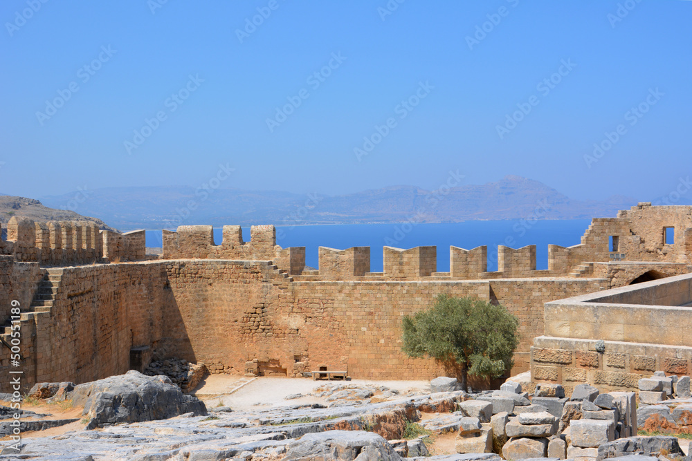ancient brick wall of greek acropolis on blue sky and mediterranean sea ...