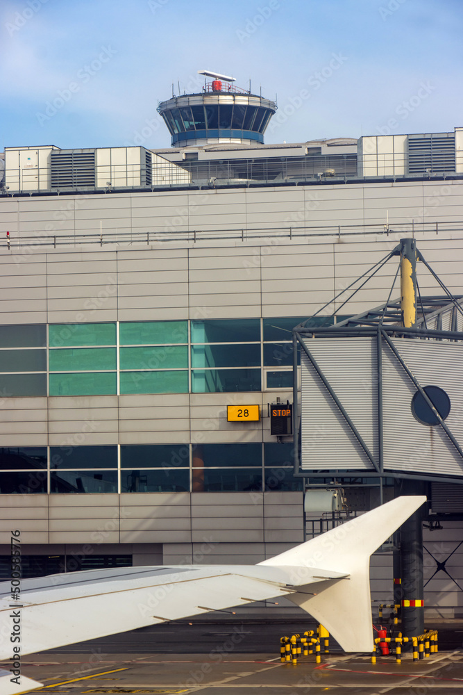 Airliner wing under the airport building with control tower Stock Photo ...