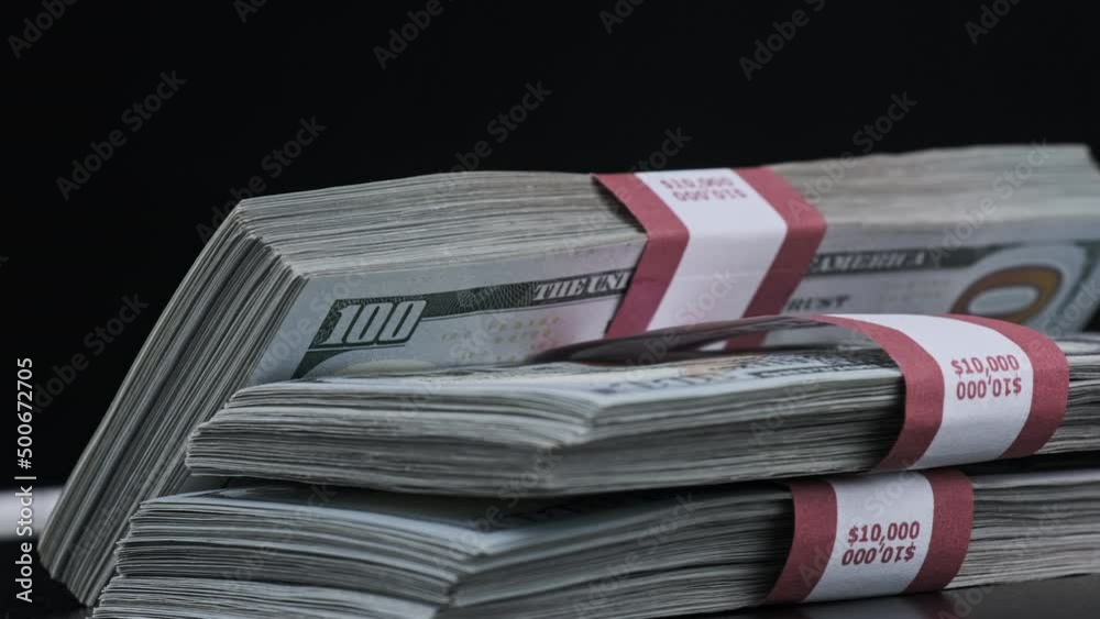 Bundles of dollars rotate on black background. Three stacks of 10000 ...