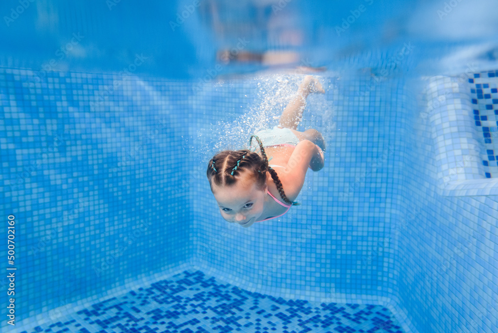 Little child girl swimming underwater in the paddling pool. Diving ...