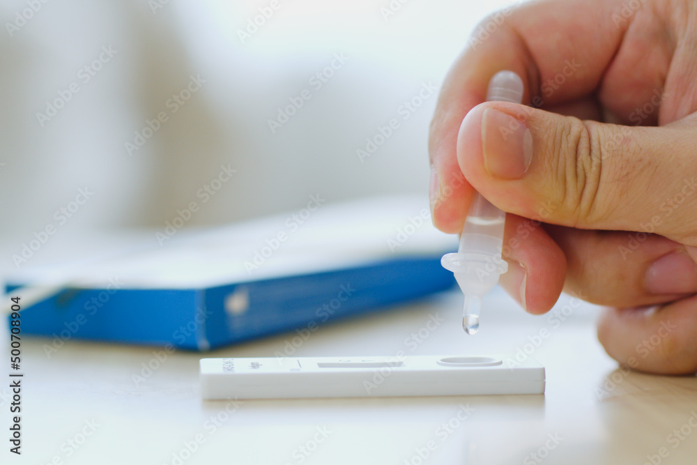 CLoseup hand using rapid antigen test kit (ATK) for self test at home ...