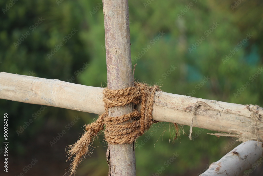 Wooden poles tied up with natural fiber ropes also called scaffolding ...