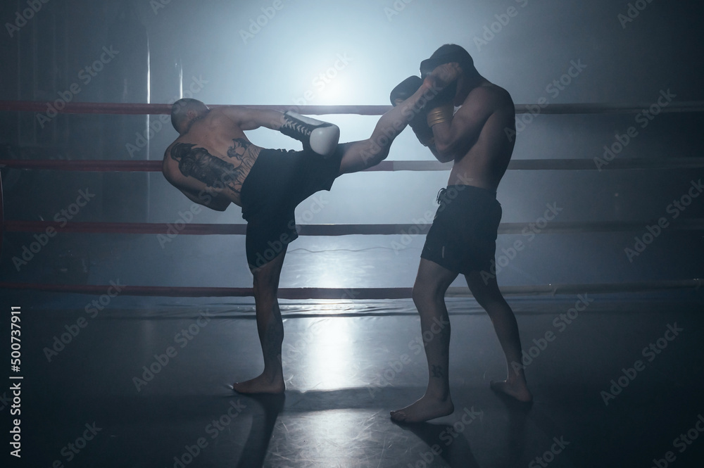 Two shirtless muscular man fighting Kick boxing combat in boxing ring ...