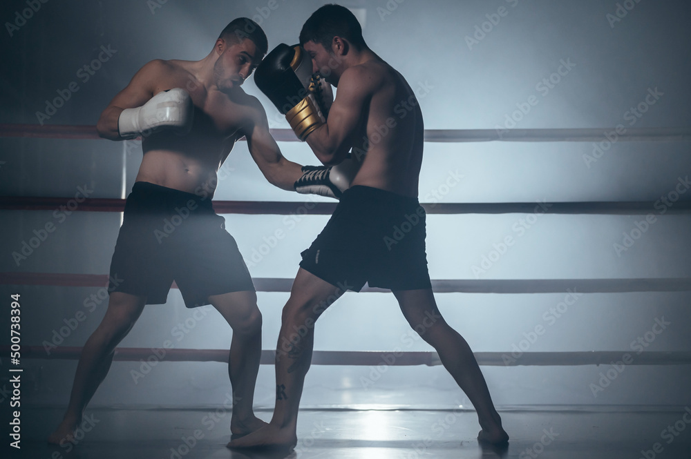 Two shirtless muscular man fighting Kick boxing combat in boxing ring ...