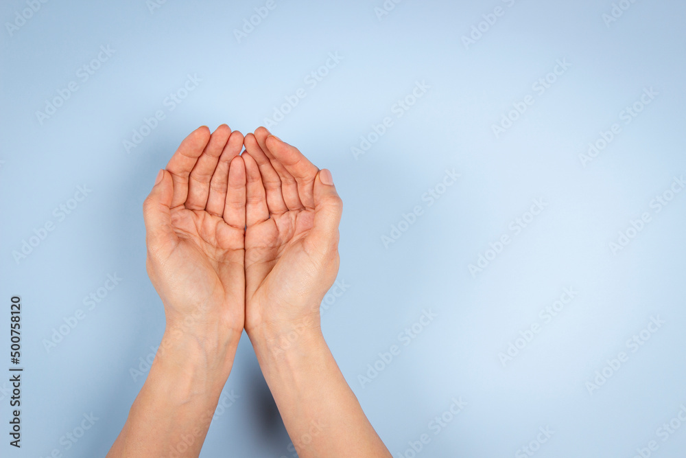 Empty cupped palm hands, keeping hands together on light blue ...