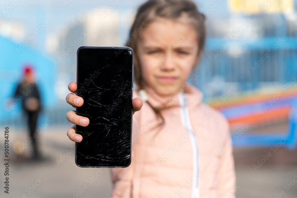Portrait of scared kid girl with broken mobile phone at skatepark. Sad ...