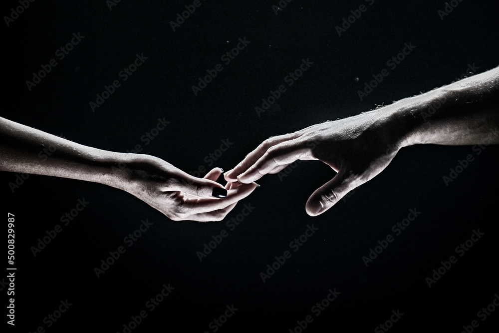 Two hands stretch each other, black background. Couple in love holding ...