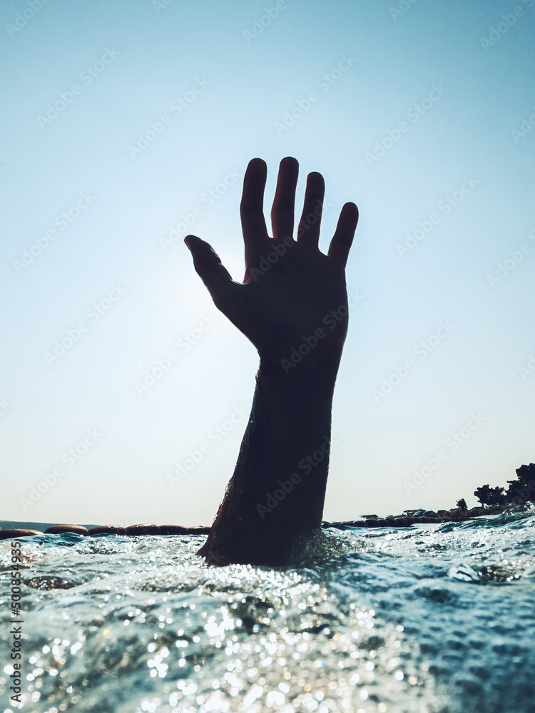 Hand of a drowning man reaching out from the deep cold sea water and ...