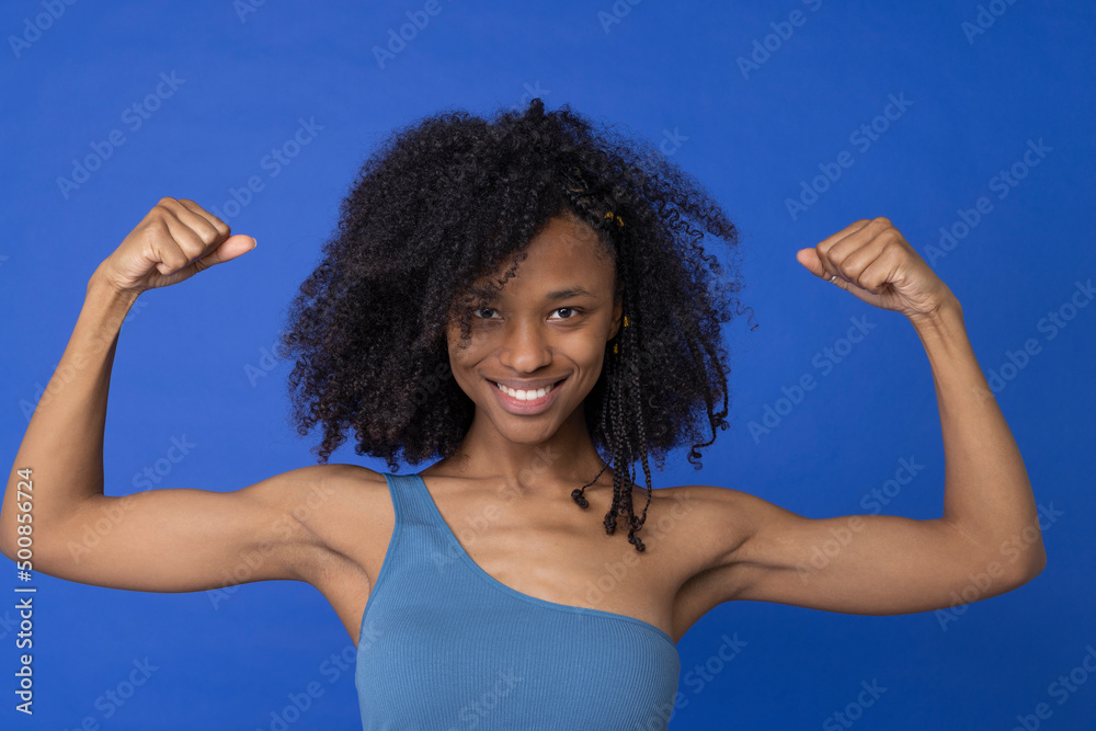 Smiling woman flexing muscles against blue background Stock Photo ...
