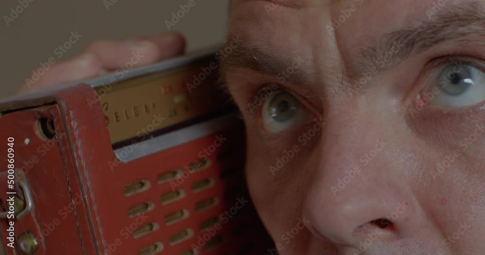 A man listens to the radio speaker in his hands. He listens to a faint ...