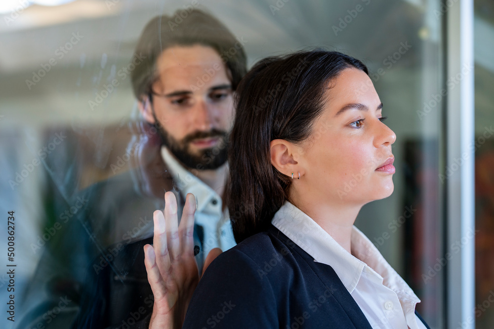 Sad man touching back of woman separated through glass pane Stock Photo ...