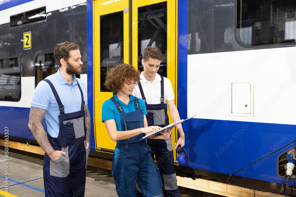 Engineer showing file folder to trainees by monorail in factory Stock ...