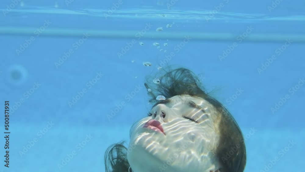 Close-up portrait of a face of a brown-haired girl who is underwater on ...