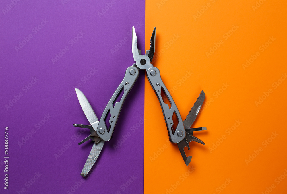 multitool lies on a multi-colored background. multitool with open tools ...