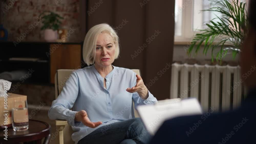 Mature woman is speaking and psychologist listening to her during ...