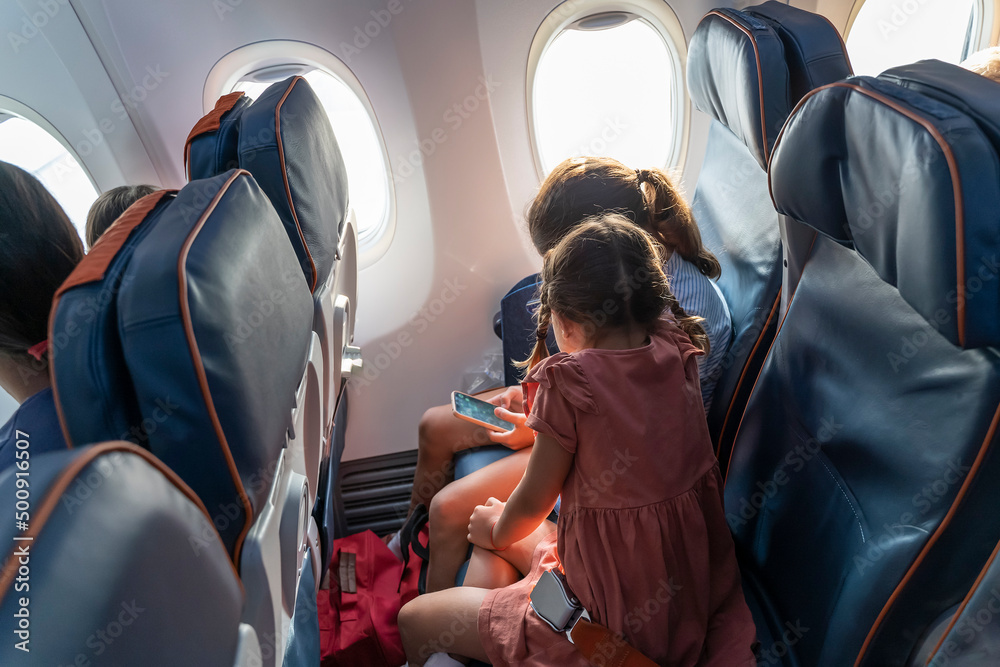 Adorable little girls travel by plane. Cute Kids sit at the window of ...