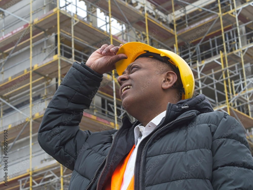 Frowning civil engineer or factory worker fixing his safety helmet and ...