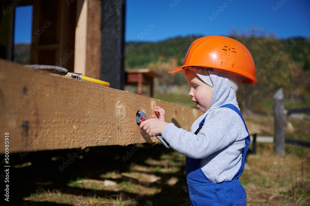 Boy toddler playing as builder on construction site. Child carpenter in ...