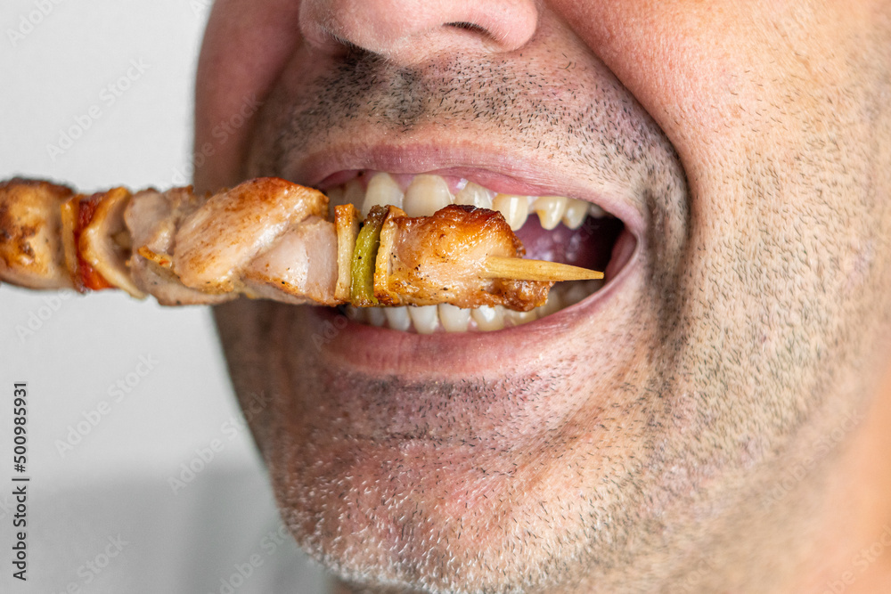 Mouth of a middle-aged man biting into a skewer of meat. Stock Photo ...
