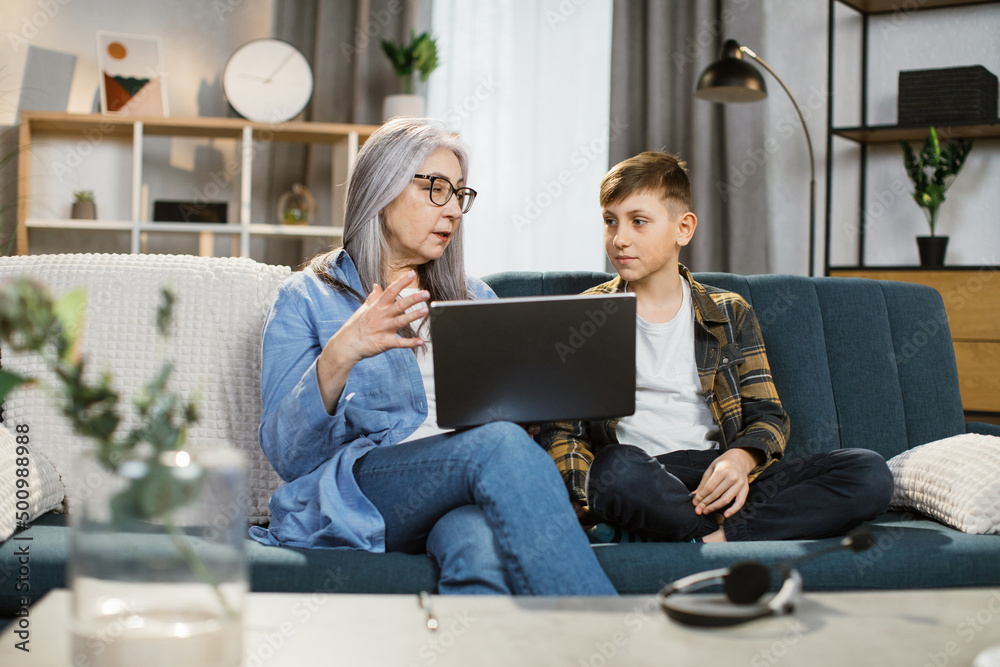 Caucasian young handsome boy teaching his old gray-haired grandmother ...