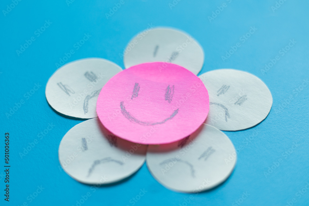 Pink paper smiley face with yellow paper sad faces around it. Concept ...