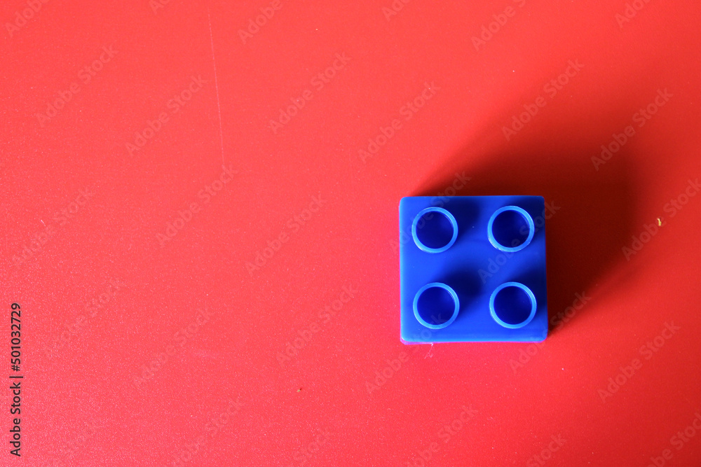 Buildable blue plastic block on a red background. Concept of loneliness ...