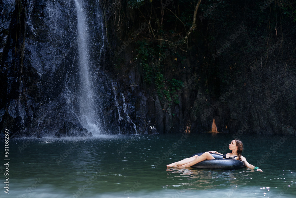 Travel and nature. Young woman swimming in tropical waterfall pool ...